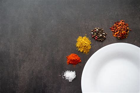 다양한 향신료가 더미에 흩어져있는 텍스트 공간이있는 흰색 빈 접시 검은 색 배경에 복사 공간 건강한 식생활에 대한 스톡 사진 및