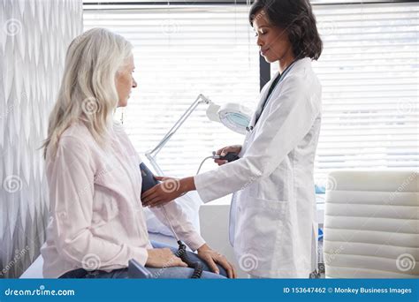 Woman Patient Having Blood Pressure Taken By Female Doctor In Office