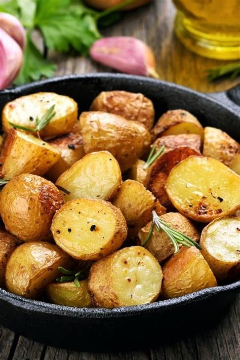 Cooked Potatoes In A Cast Iron Skillet With Rosemary Garnish On The Side