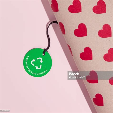 하트가 있는 재활용 포장지와 분홍색 배경에 재활용 재료로 만든이라는 문구가 있는 녹색 종이 라벨 생태 개념입니다 모형 개념에
