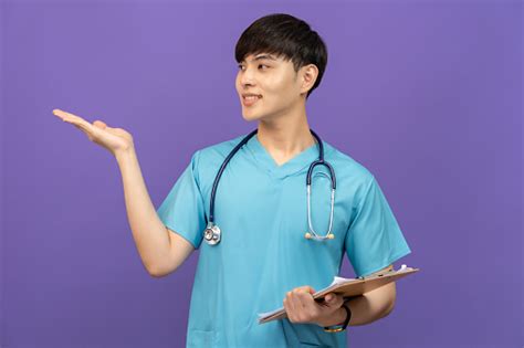 흰색과 청진기를 착용한 의사는 보라색 고립된 배경에서 카메라를 들여다보고 공간을 복사합니다 25 29세에 대한 스톡 사진 및 기타 이미지 Istock