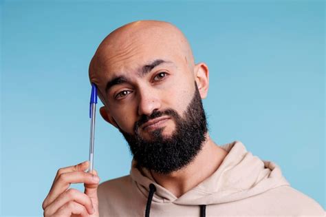 premium photo puzzled arab man rubbing head with pen while thinking