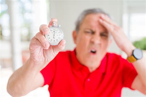 카운트 다운을 보여주는 스톱 와치를 들고 잘 생긴 노인은 수치심과 깜짝 얼굴 분노와 좌절에 충격 머리에 손으로 스트레스 실수에 대한 두려움과 화가 마음이 산란해진에 대한