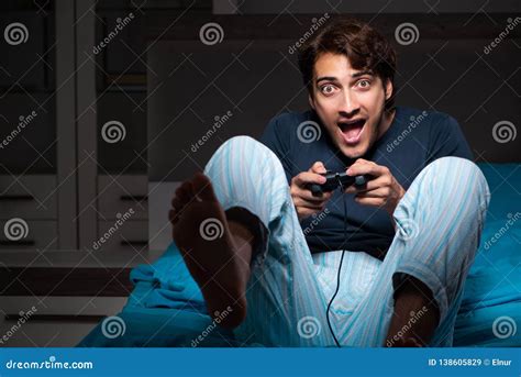 The Young Man Playing Computer Games At Night In Bed Stock Image