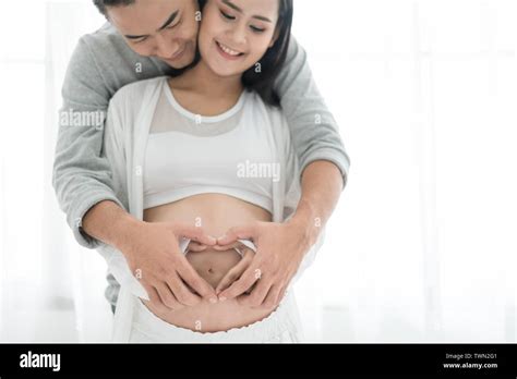 Asian Beautiful Pregnant Woman And Her Handsome Husband Hugging The