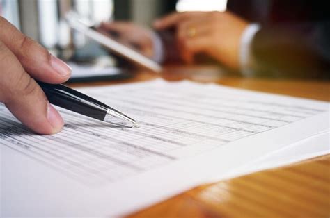 Premium Photo Cropped Hand Of Business Person Holding Pen On Paper In