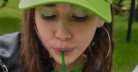 초록색 모자를 쓴 여자가 초록색 병에 담긴 물을 마시고 있다 사진 Unsplash의 브랫 그린 이미지