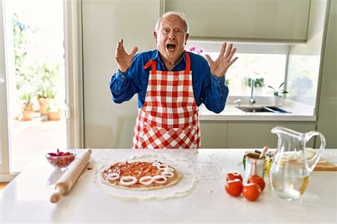 행복한 미소와 승자 표정으로 승리를 축하하는 홈 키친에서 회색 머리 요리 피자를 가진 시니어 맨 긍정적인 감정 표현에 대한 스톡 사진 및 기타 이미지 Istock