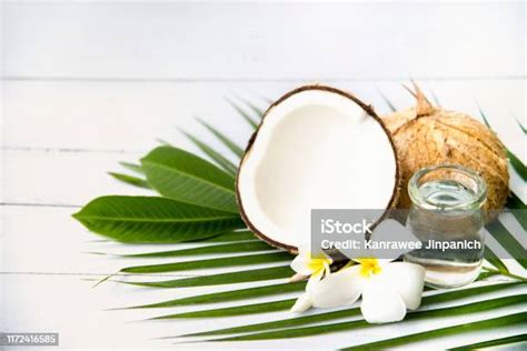 흰색 나무 배경에 Frangipani 꽃 오일과 녹색 야자수 잎 병에 코코넛 오일 건강 식품 스킨 케어 컨셉 여름 플랫 레이