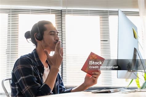 집에서 여자 친구 나 가족과 함께 컴퓨터로 화상 통화를하면서 선물 상자를 보여주는 행복한 젊은 아시아 남자 거리 관계 코로나 바이러스 전염병 기간 동안 새로운 정상적인 축하