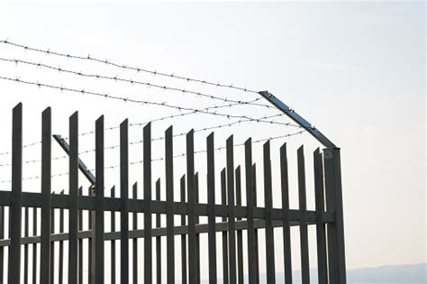 空に面した有刺鉄線のある背の高い鉄の柵刑務所や危険な施設の誕生境 カラー画像のストックフォトや画像を多数ご用意 カラー画像