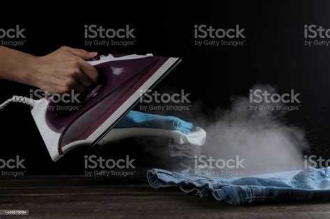 소녀는 검은 배경에 옷에 라일락 철의 증기를 허용합니다 다림질 옷 가정용 전기 제품 가사 집안일에 대한 스톡 사진 및 기타