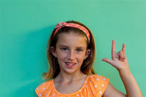 Caucasian Schoolgirl Doing Sign Language Gesture Over Blue Background
