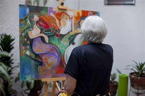一名60岁的拉丁妇女在自家后院画着一幅美丽的画，人们从后面拍照模板素材 稿定设计
