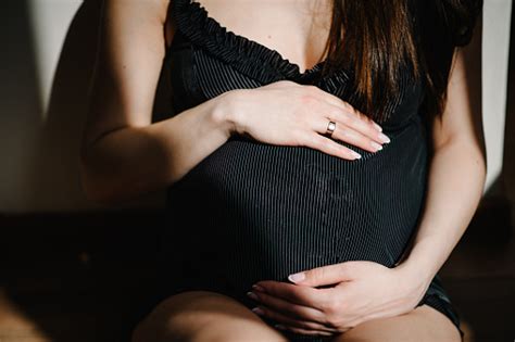 아기를 기다리고 있습니다 임신한 여 자가 앉아 손과 위 둥근 배를 포용 클로즈업입니다 9 개월입니다 베이비 샤워입니다 어머니