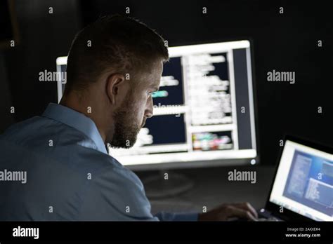 Programmer Working Late At Night On Multiple Computer Screens Stock