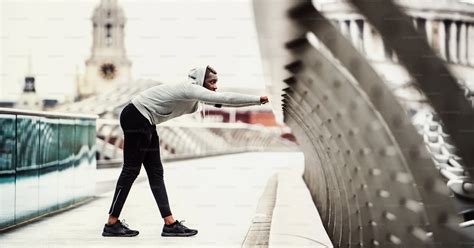 젊은 스포티 한 흑인 남자가 도시의 다리에서 스트레칭을합니다 사진 Unsplash의 사진술 이미지