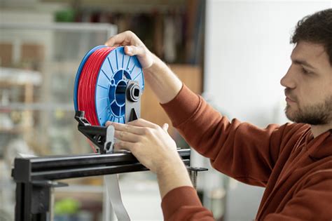 젊은 디자이너는 새로운 항목을 인쇄하는 3d 프린터에 빨간 필라멘트로 스풀을 넣어 검사 보기에 대한 스톡 사진 및 기타 이미지 검사 보기 공장 산업 건물 기계공