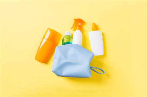 선크림 스프레이 선스린 선블록 바디 로션 Spf 크림이 가득한 여성 화장품 가방의 탑 뷰를 복사 공간이 있는 노란색 배경에