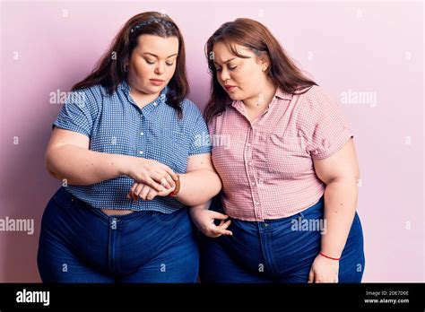 Young Plus Size Twins Wearing Casual Clothes Checking The Time On Wrist