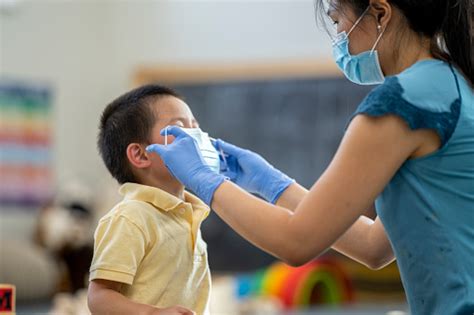 아이가 보호 얼굴 마스크를 착용하는 데 도움이 보육 촉진기 2명에 대한 스톡 사진 및 기타 이미지 2명 4 5세