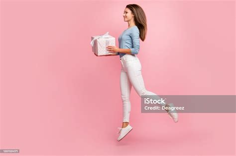 명랑 한 긍정적 인 귀여운 예쁜 예쁜 여자 친구가 미소 짓는 미소짓는 선물 상자를 리본으로 실행하여 고립 된 파스텔 색상 배경을