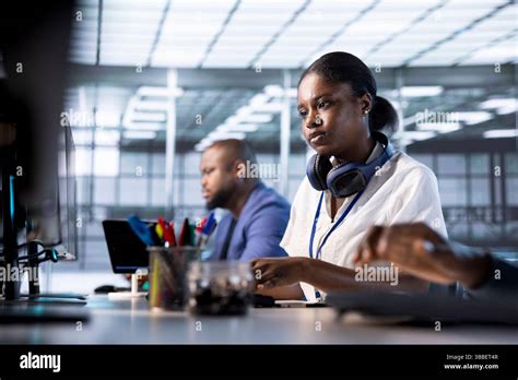 African American Engineer Next To Coworkers In Server Farm Checking