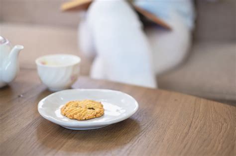 아시아 노인 여성은 집 소파에서 쿠키를 손에 들고 휴일을 위해 노트에 메모를 적고 있습니다 휴식과 휴식의 개념 가정 생활에 대한