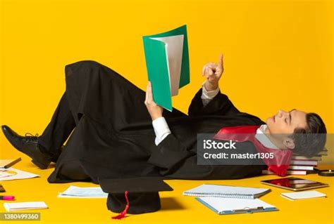 젊은 남자의 초상화 졸업 하 송의 학생 바닥에 누워 서 독서 종이 고립 된 Oer 노란색 스튜디오 배경 18 19세에 대한 스톡
