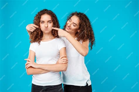 Free Photo Woman Smiling Touching Cheeks Her Sister Twin Over Blue