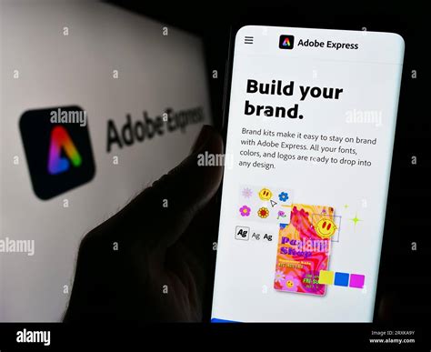 Person Holding Cellphone With Webpage Of Graphics Design Software Adobe Express On Screen In