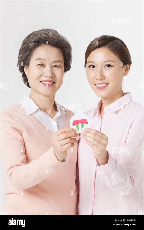 Mother And Grown Up Daughter Holding A Picture Of Carnation Together