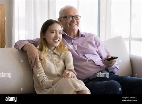 Pre Teen Girl And Grandpa Spend Time Together Watching Movie Stock