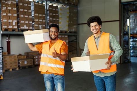 쾌활하고 근면한 두 명의 인종 간 보관 노동자가 상자를 들고 창고에 서서 선적을 준비하고 있습니다 2명에 대한 스톡 사진 및 기타 이미지 Istock