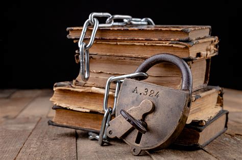 舊書被一條新的閃亮的鏈子綁著 那是一把舊掛鎖禁止在木桌上的老作品演出者黑暗的背景 照片檔及更多 保安 照片 保安 保護 加密 Istock