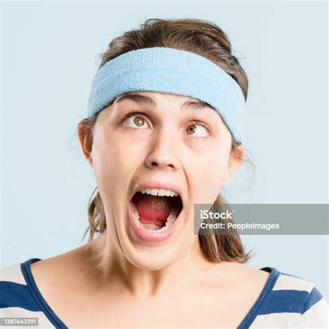 스튜디오에 홀로 서서 머리띠를 쓰고 재미있는 얼굴을 당기는 매력적인 젊은 여성의 샷 25 29세에 대한 스톡 사진 및 기타