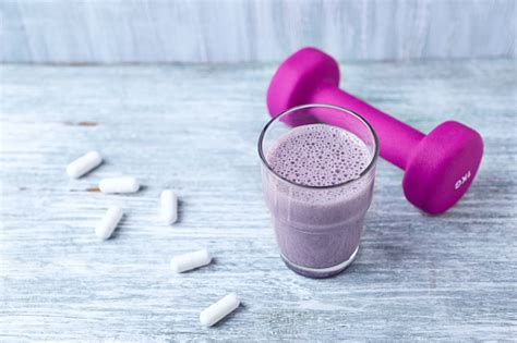 우유와 블루베리를 사용한 단백질 쉐이크 Bcaa 아미노산 및 바이올렛 아령 배경 스포츠 영양 소박한 나무 배경입니다 복사 공간