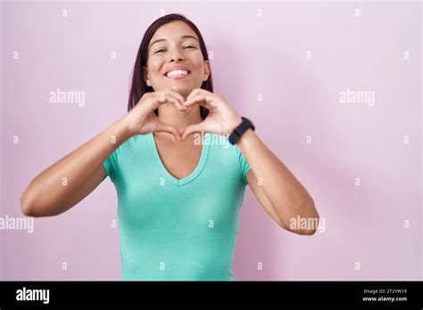 Young Hispanic Woman Standing Over Pink Background Smiling In Love