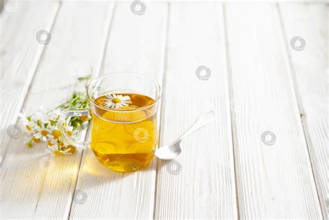 Чашка травяного чая с цветами ромашки на белом деревянном фоне Концепция натуральной