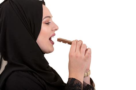 흰색 배경에 고립 된 초콜릿을 먹는 Hijab와 사랑 스러운 미소 회교도 여자 건강에 좋지 않은 음식에 대한 스톡 사진 및 기타