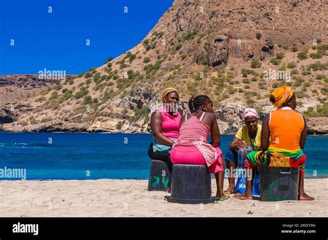 Dark Skinned Women Sitting At Sandbeach And Talking To Each Other