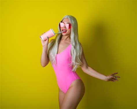 A Loira Com Uma Bela Bunda Grande Em Um Maiô Rosa Bebe Uma Bebida