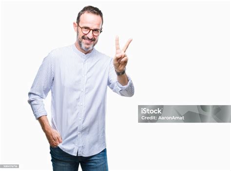 중 년 노인의 수석 사람 승리 표시를 하 고 카메라에 윙크 하는 행복 한 얼굴로 웃 고 고립 된 배경 위에 안경을 쓰고 번호 2