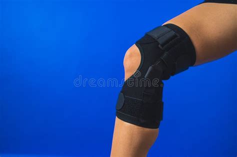 Woman Adjusting A Knee Support Brace Closeup Shot Blue Background