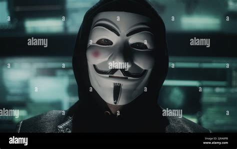 Male Web Hacker In Hood And Anonymous Mask Looking At Camera During