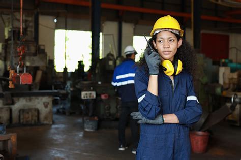 중공업 제조 공장에서 유지 보수 작업 선반 금속 기계를 제어하는 동안 워키토키 라디오를 사용하는 보호복을 입은 기술자 또는