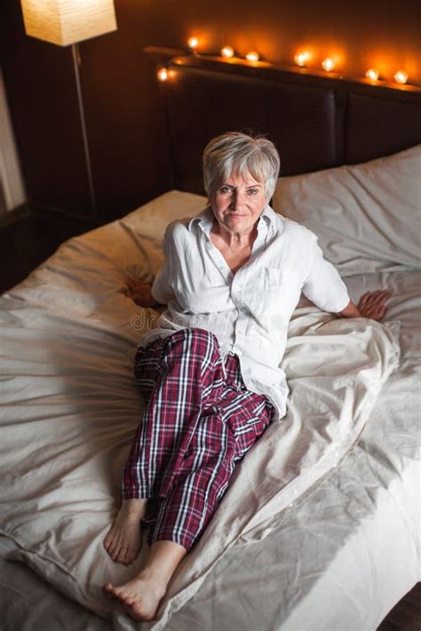 Mulher Idosa Esticada Na Cama Acordando Em Casa Foto De Stock Imagem