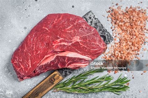 생 프라임 소고기 스테이크 탑 등심 또는 분홍색 소금과 로즈마리를 곁들인 럼프가 있는 정육점 보드 회색 배경 위쪽 보기 탑설로인