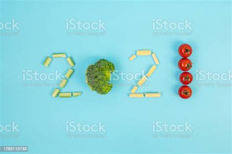 2021 새해 복 많은 새해 와 야채와 새로운 당신 오이 아기 옥수수 체리 토마토와 브로콜리는 파란색 배경에 배열 목표 건강