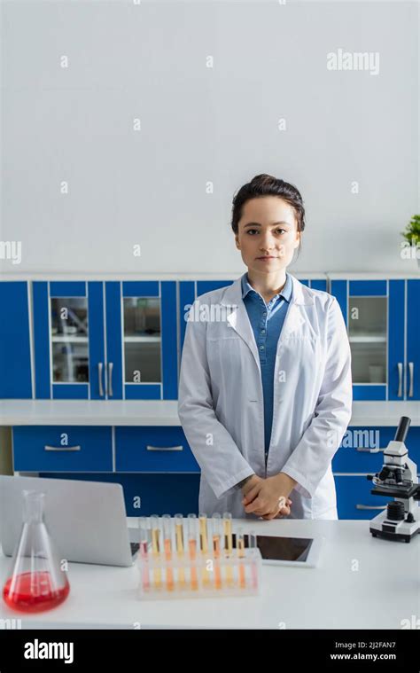 Young Bioengineer Looking At Camera Near Devices And Microscope In Lab
